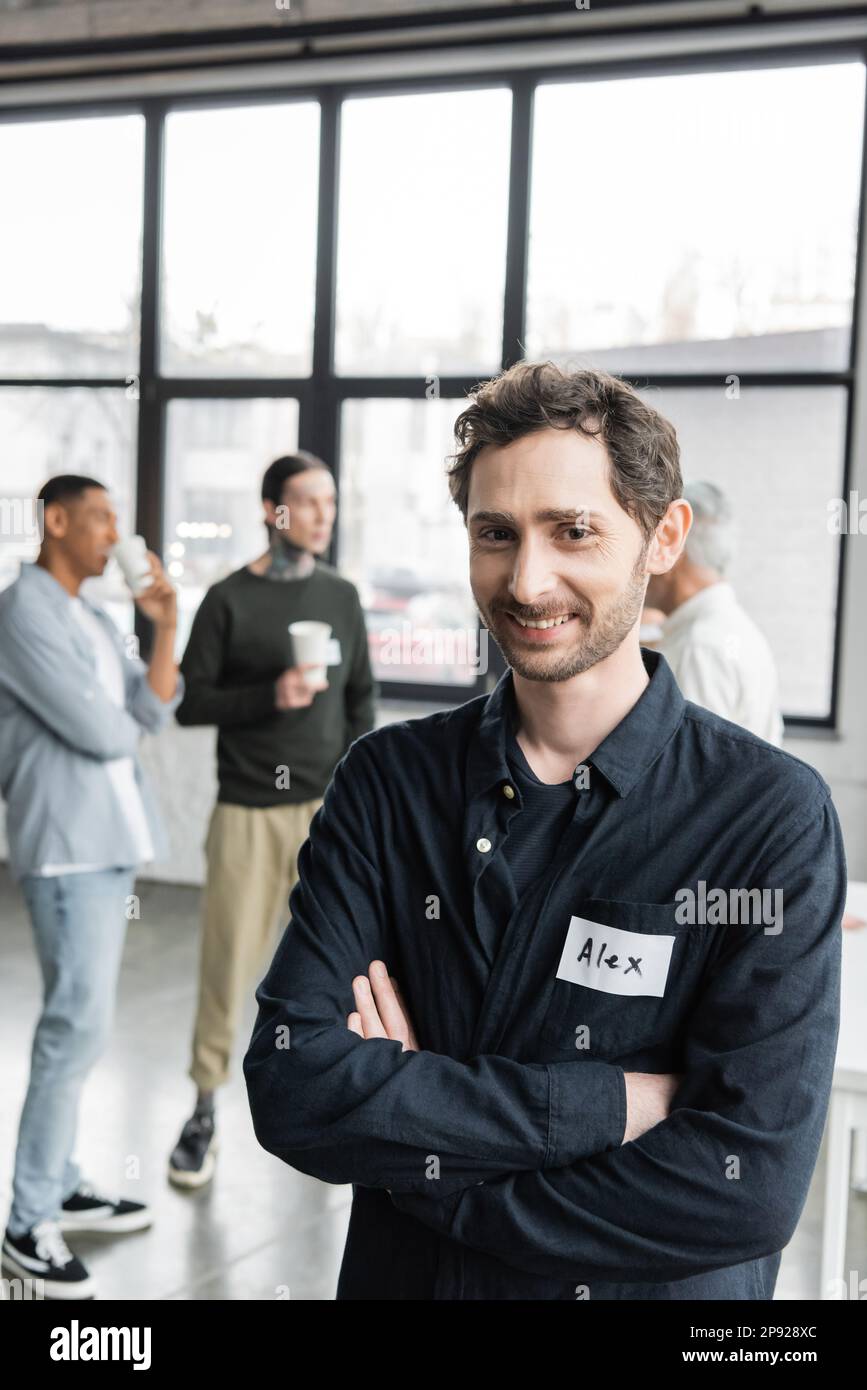 Positive man with name sticker crossing arms during alcoholics meeting ...