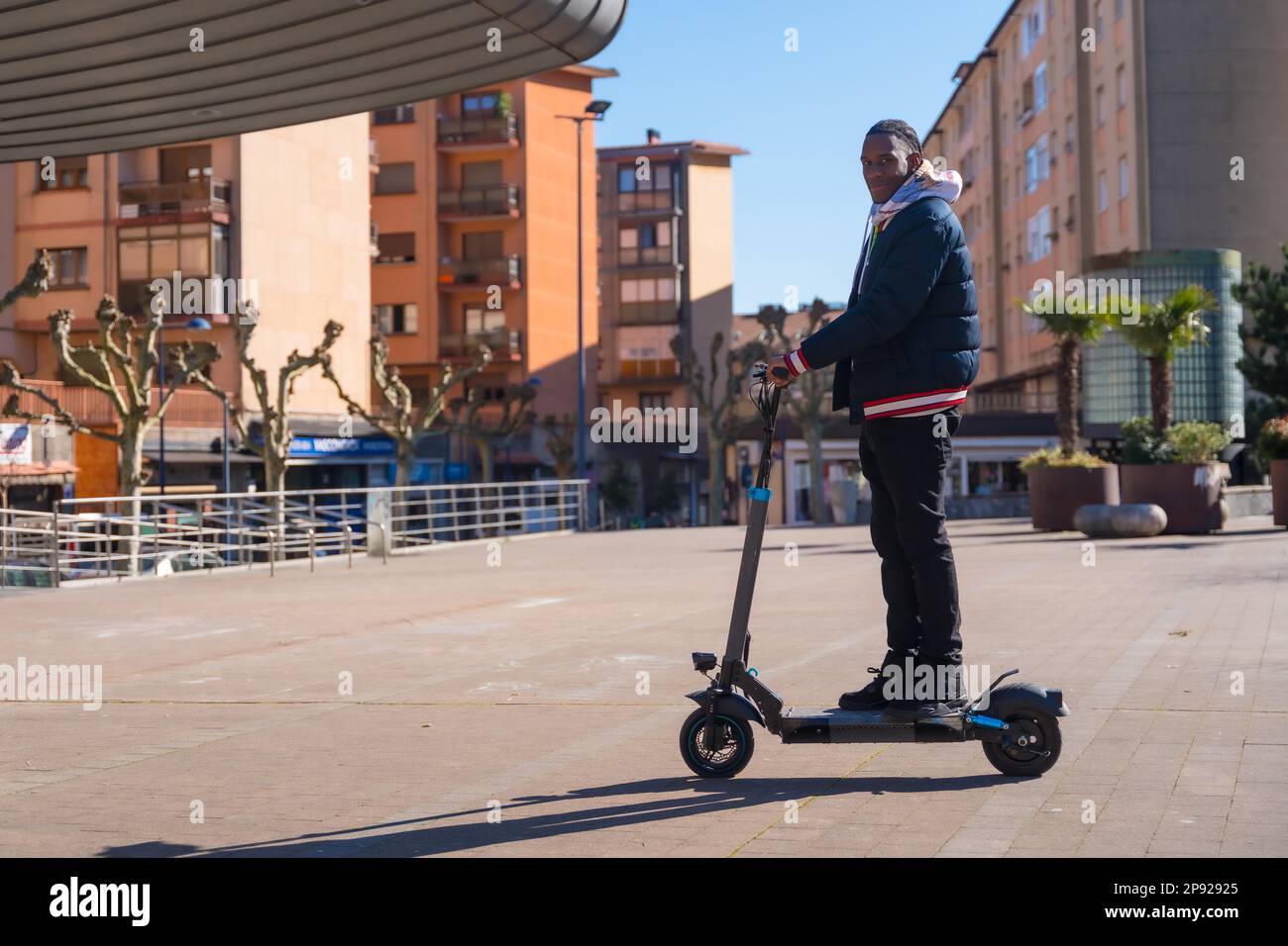 Black ethnic male skateboarding on an electric skateboard, green and ...