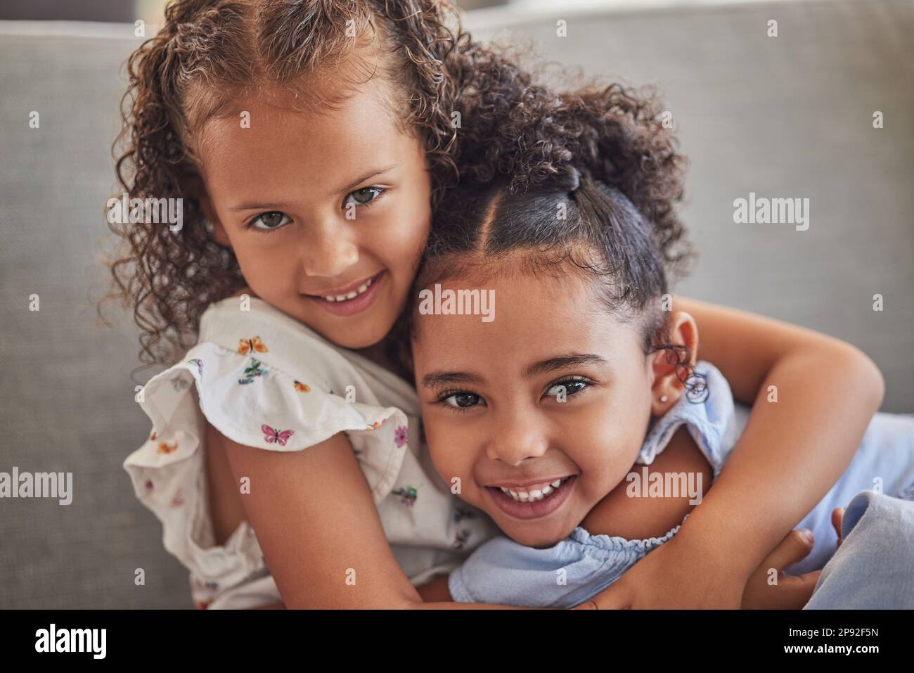 Happy, smile and portrait of sisters hugging while sitting on a sofa in ...