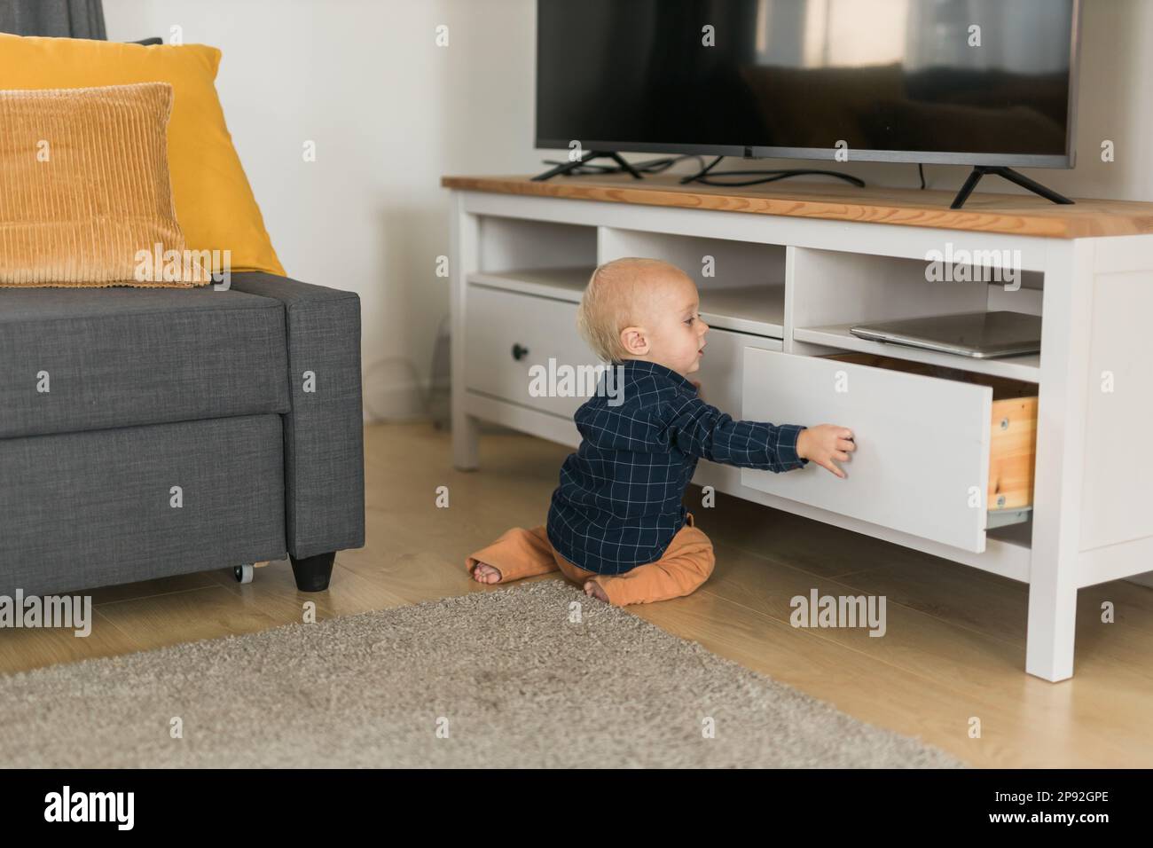 Toddler baby boy open cabinet drawer with his hand. Child explore what ...