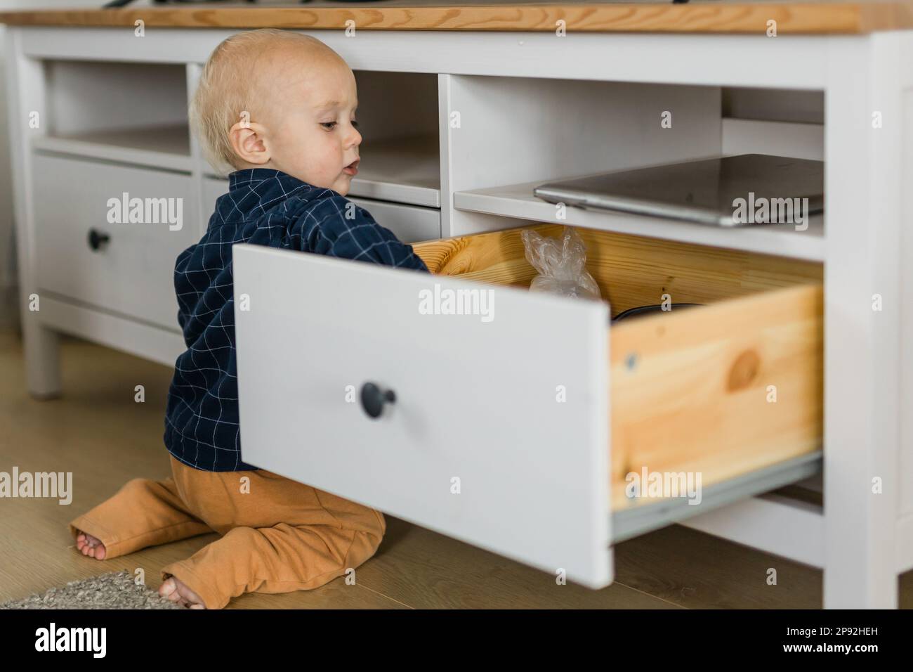 Toddler baby boy open cabinet drawer with his hand. Child explore what ...