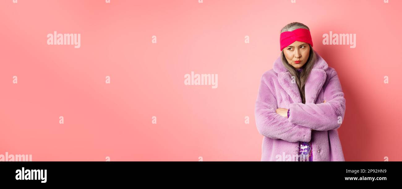 Grumpy funky old asian lady looking from under forehead, pouting and ...