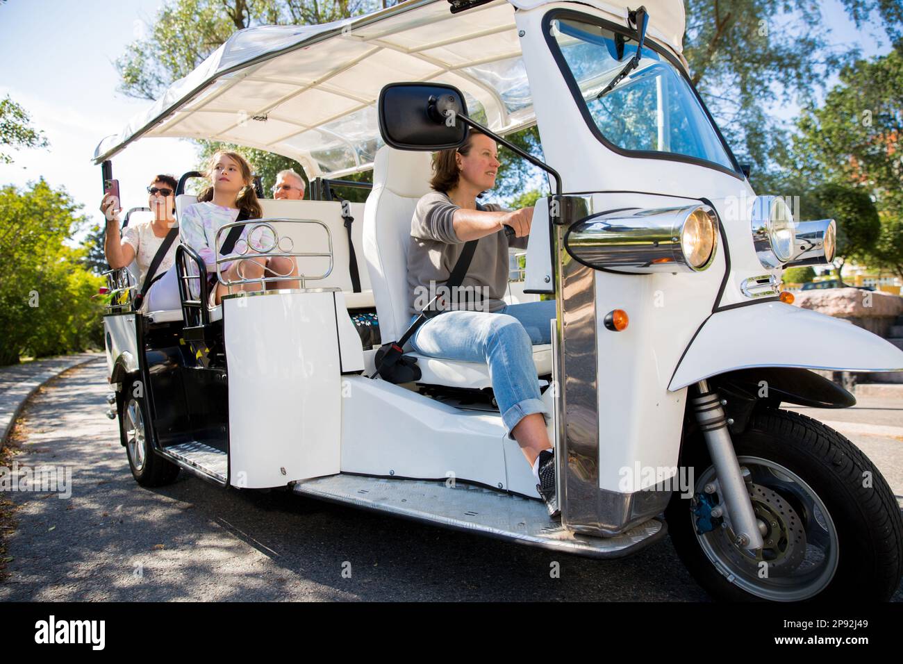 A group of tourists driving through the city center in tuk-tuk electric car. Travelers enjoying ...