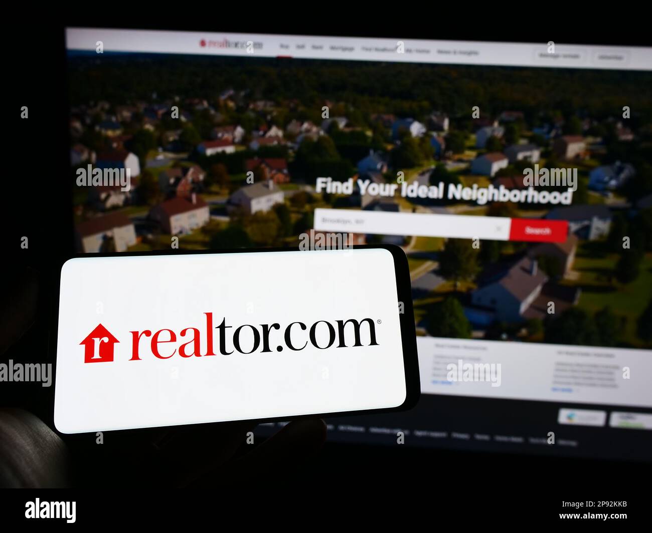Person holding cellphone with logo of AMerican real estate platform ...