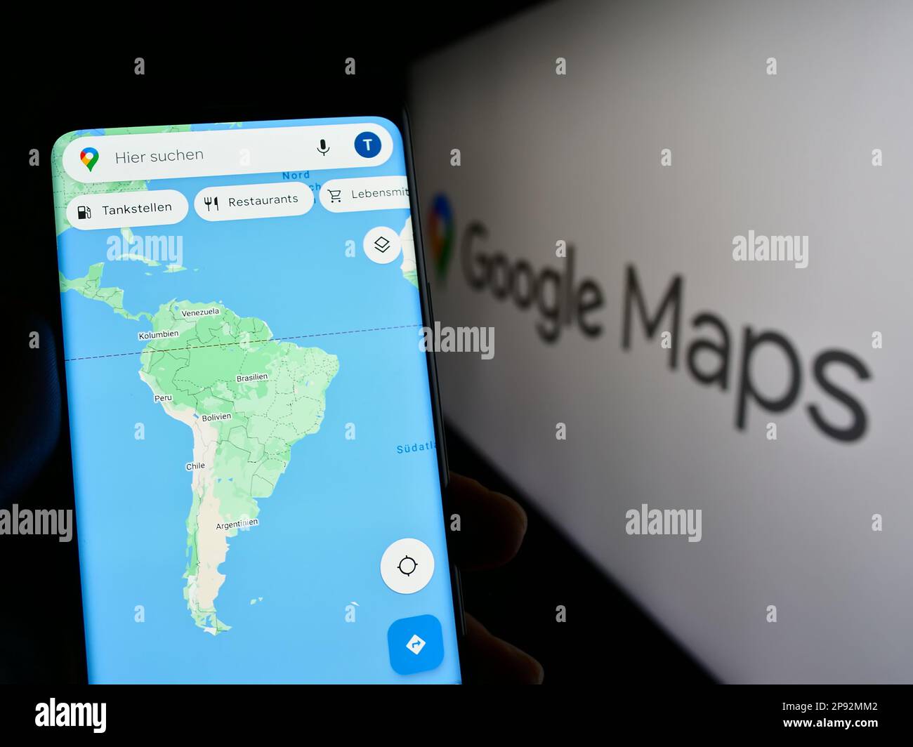 Person holding cellphone with web page of web mapping platform Google ...