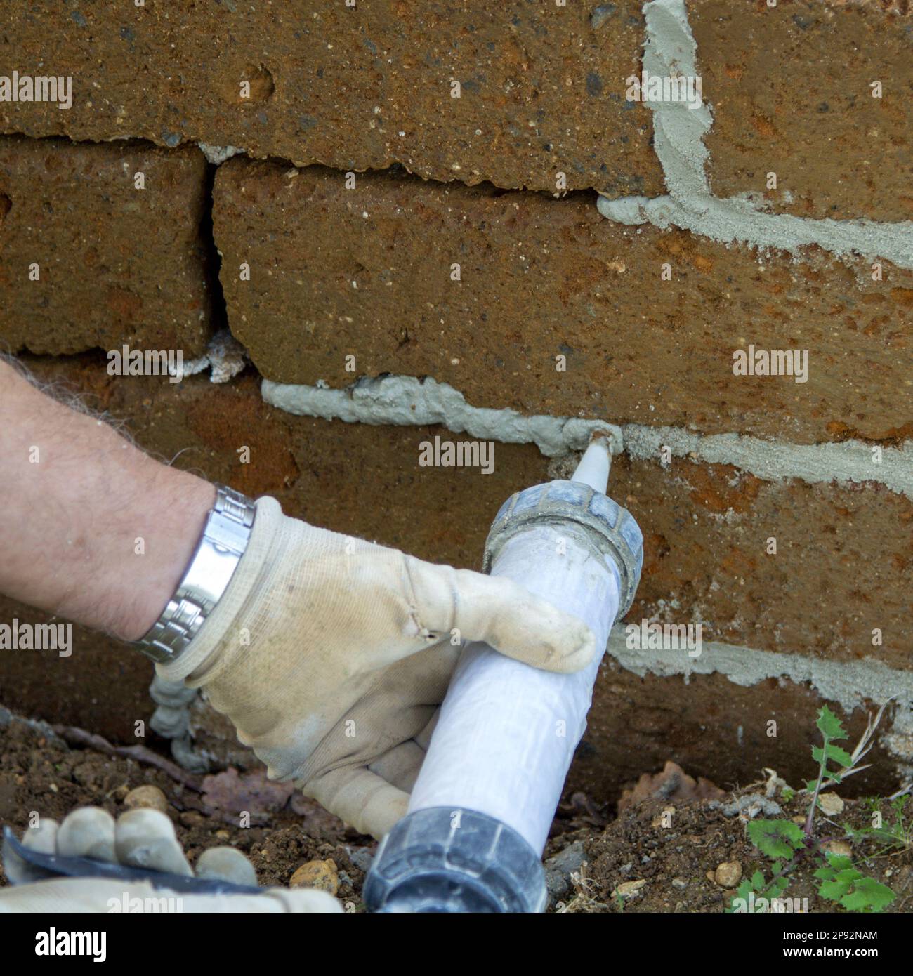 Image of the hands of a mason while filling joints in a tuff brick wall ...