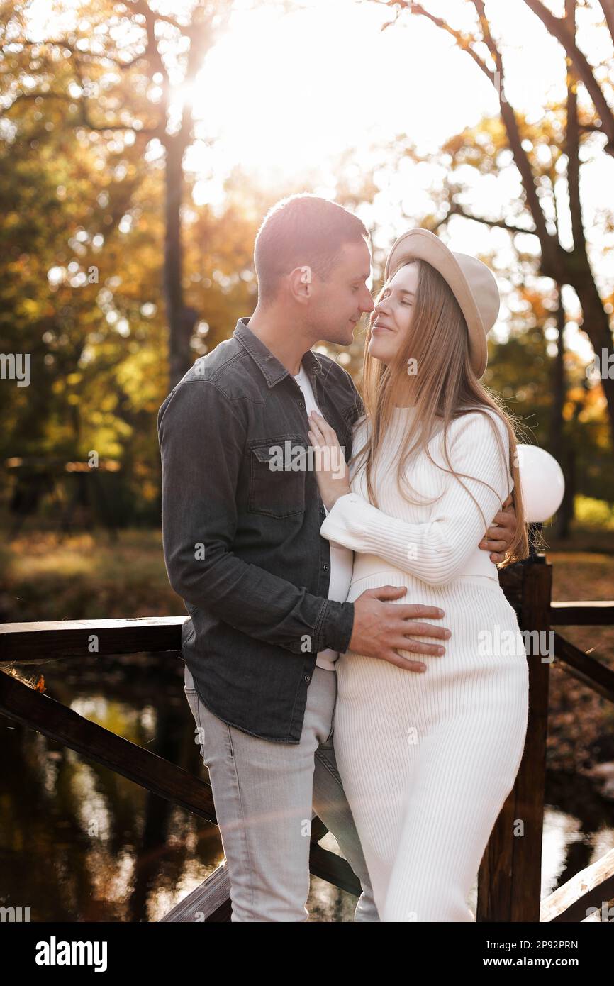Happy stylish pregnant woman and man hugs, kiss, touches belly and ...
