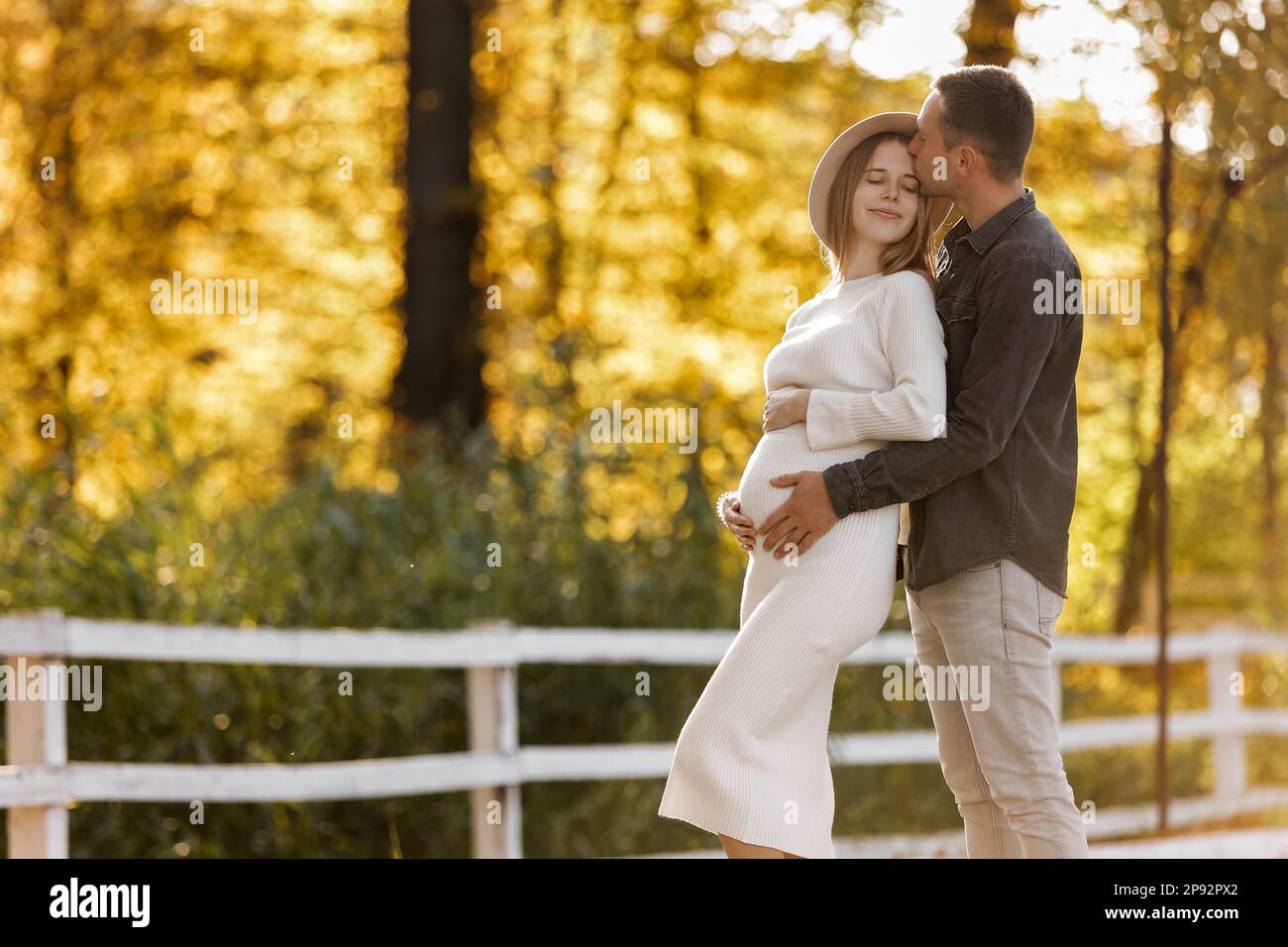 Happy stylish pregnant woman and man hugs, kiss, touches belly and ...