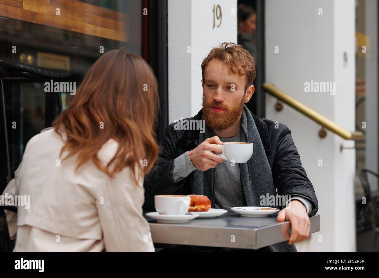Couple drinking coffee and laughing talking to each other sitting at ...