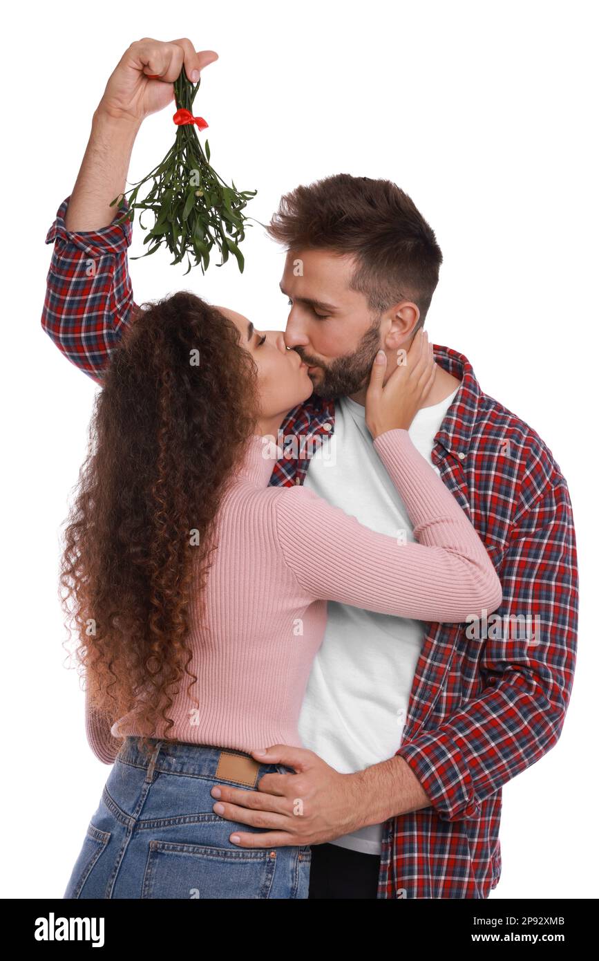 Happy couple kissing under mistletoe bunch on white background Stock ...