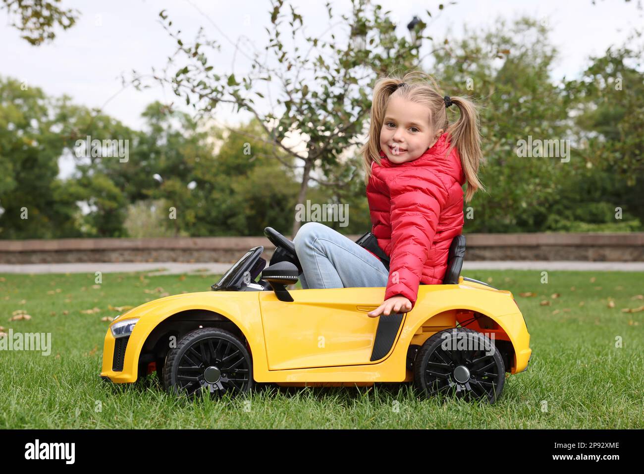 Cute little girl driving children's car in park Stock Photo - Alamy
