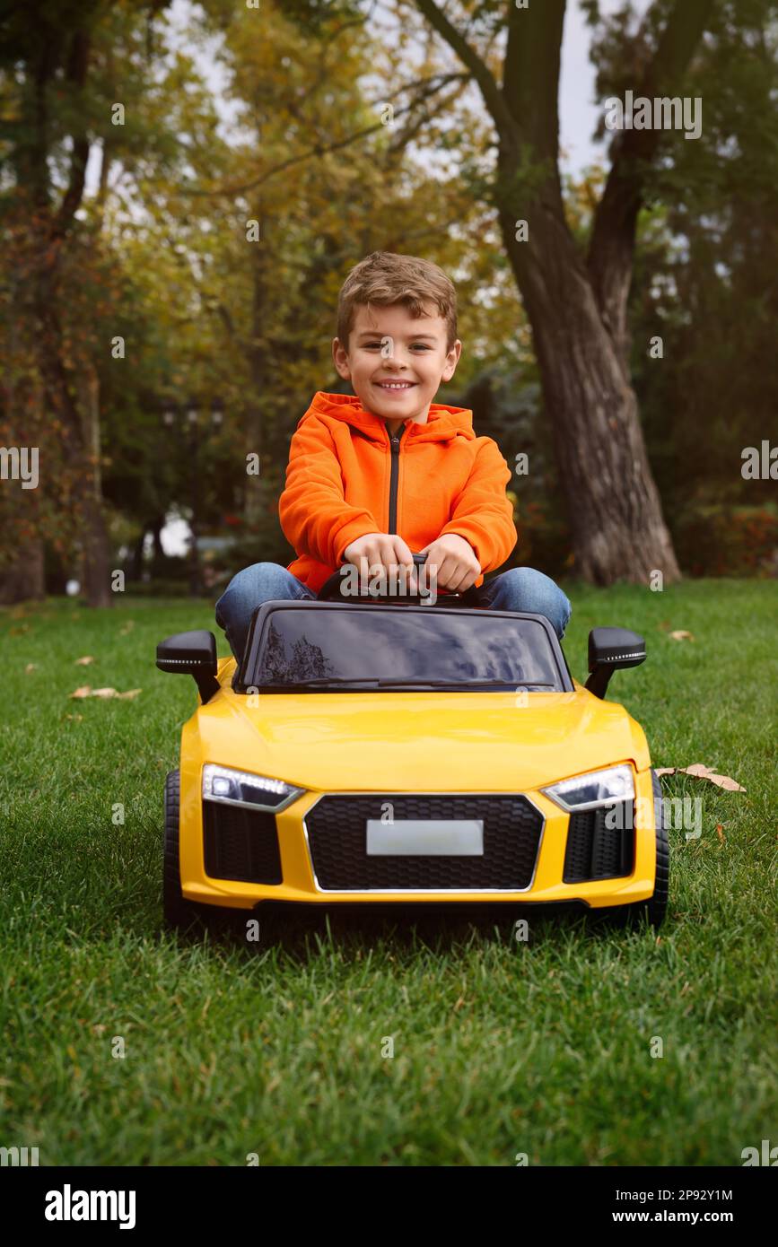Cute little boy driving children's car in park Stock Photo - Alamy