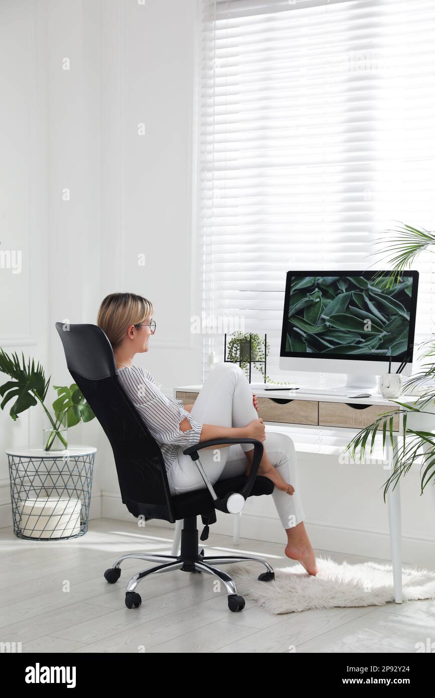Woman resting on chair near workplace in room. Interior design Stock ...