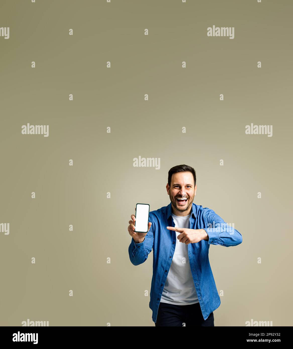 Excited man laughing and pointing at smart phone with white screen ...