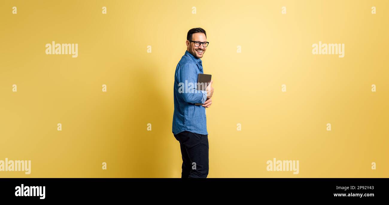 Portrait Of Smiling Handsome Male Freelancer Holding Laptop Profile Of