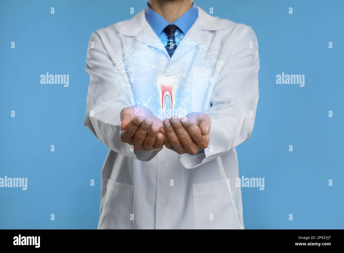 Dentist showing virtual model of tooth on light blue background ...