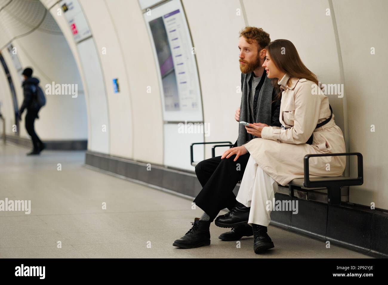Couple is sitting on a subway station bench Stock Photo - Alamy