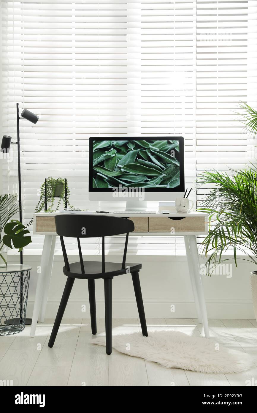 Comfortable workplace with modern computer and green plants in room ...