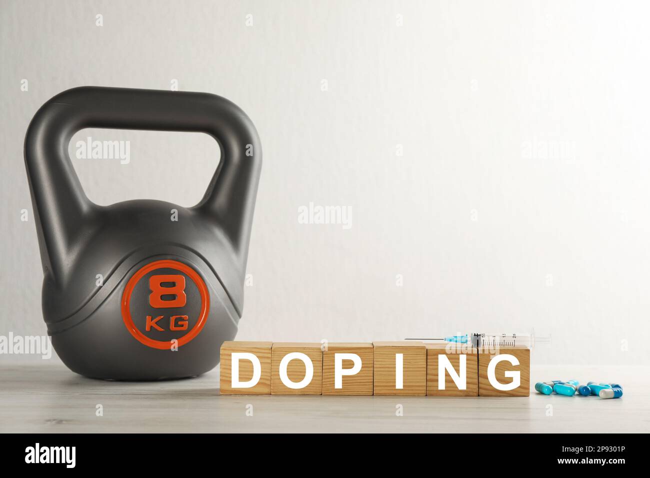 Wooden cubes with word Doping, drugs and kettlebell on table. Space for ...