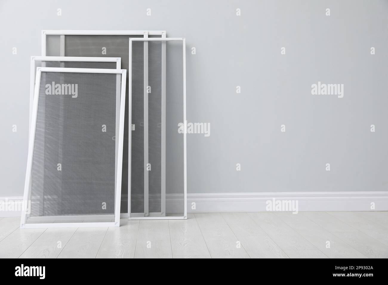 Set of window screens near light grey wall indoors. Space for text ...
