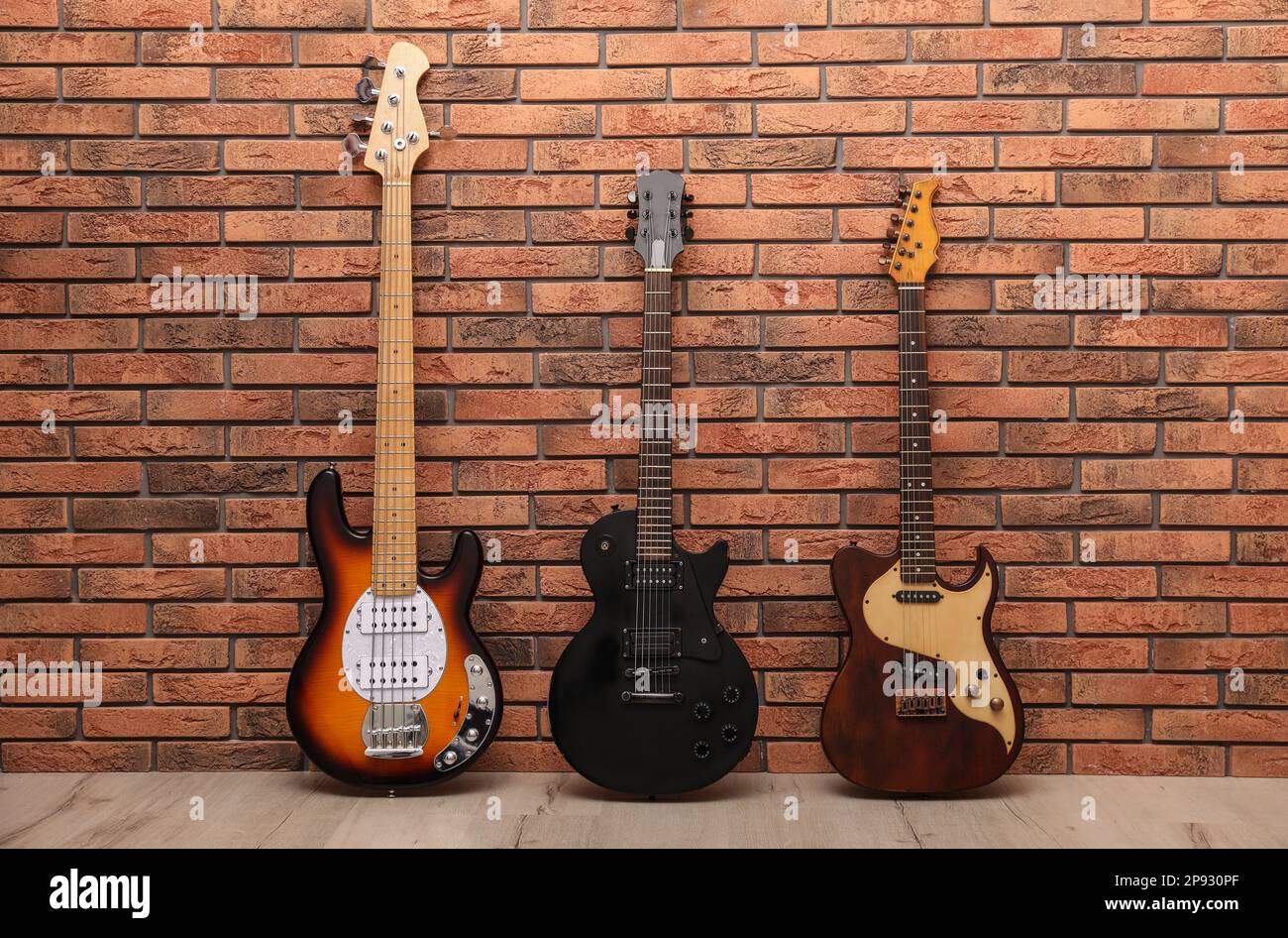 Modern electric guitars near red brick wall indoors. Band practice ...