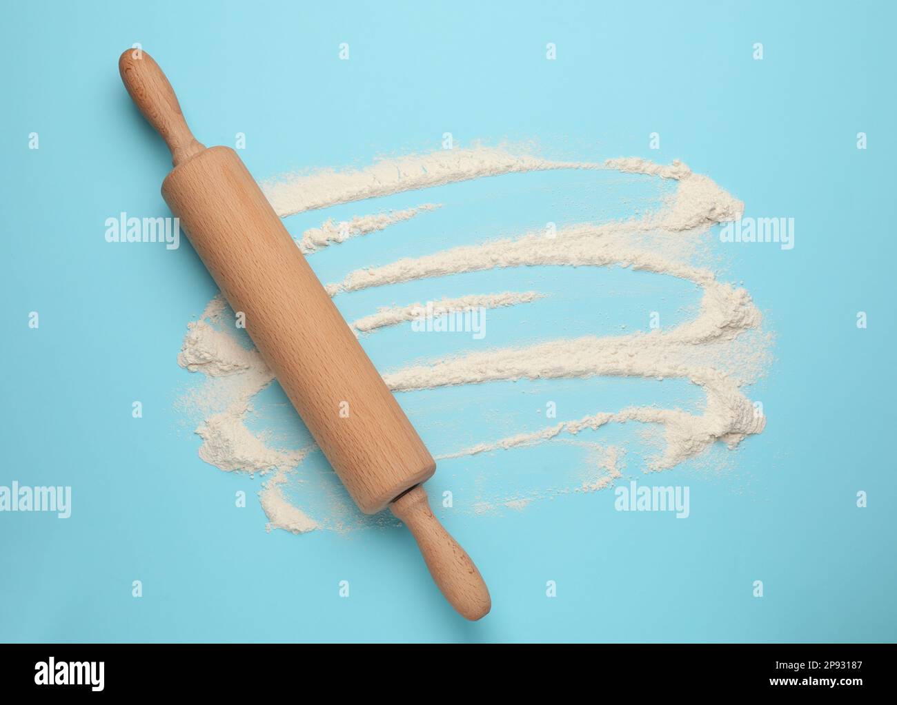 Wooden rolling pin and flour on light blue background, top view. Space ...