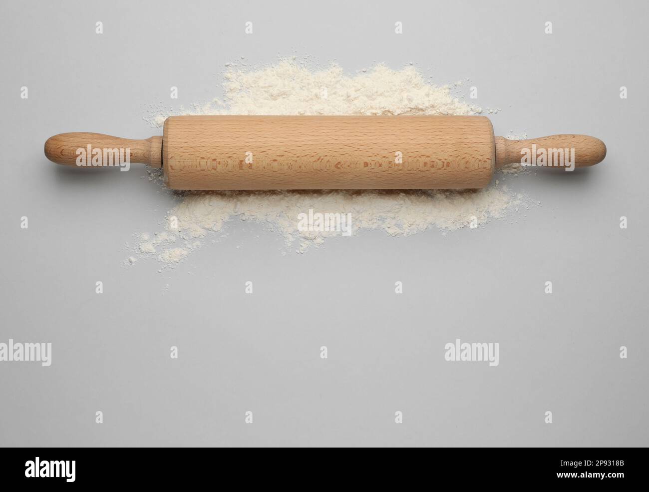 Wooden rolling pin and flour on light grey background, top view. Space ...