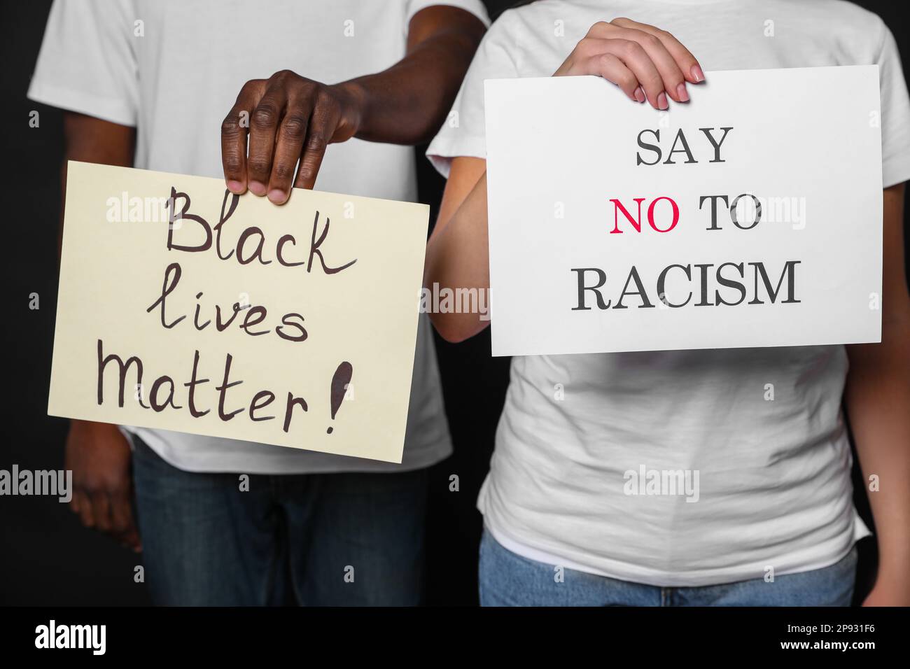 Young woman and African American man holding signs on black background ...