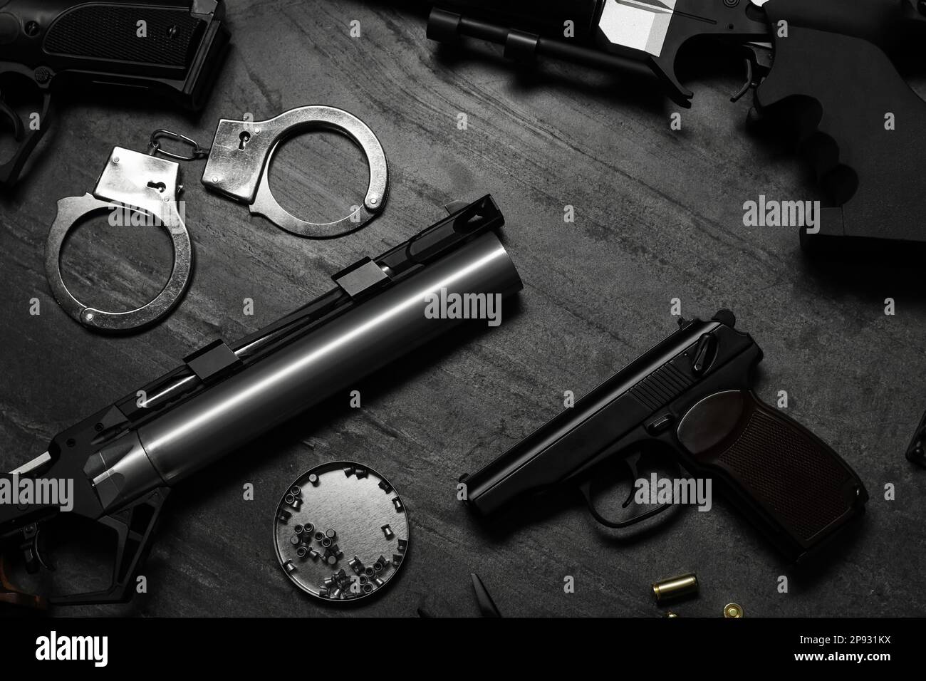 Flat lay composition with different guns on dark table Stock Photo - Alamy