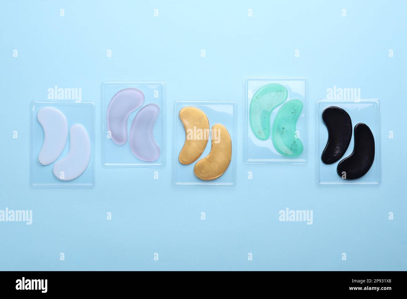 Packages of different under eye patches on light blue background, flat ...