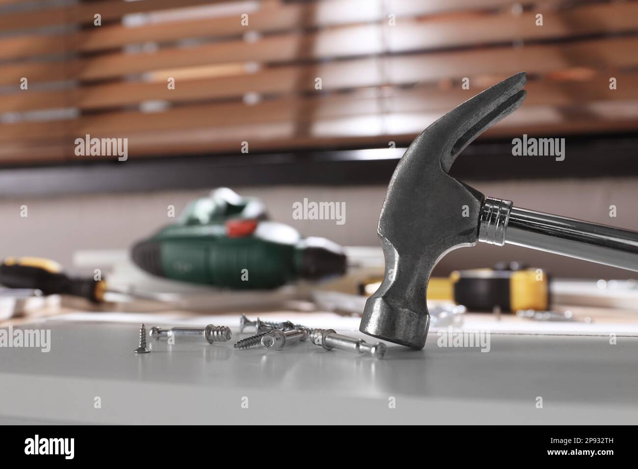 Set of different fasteners and hammer on white table indoors. Furniture ...