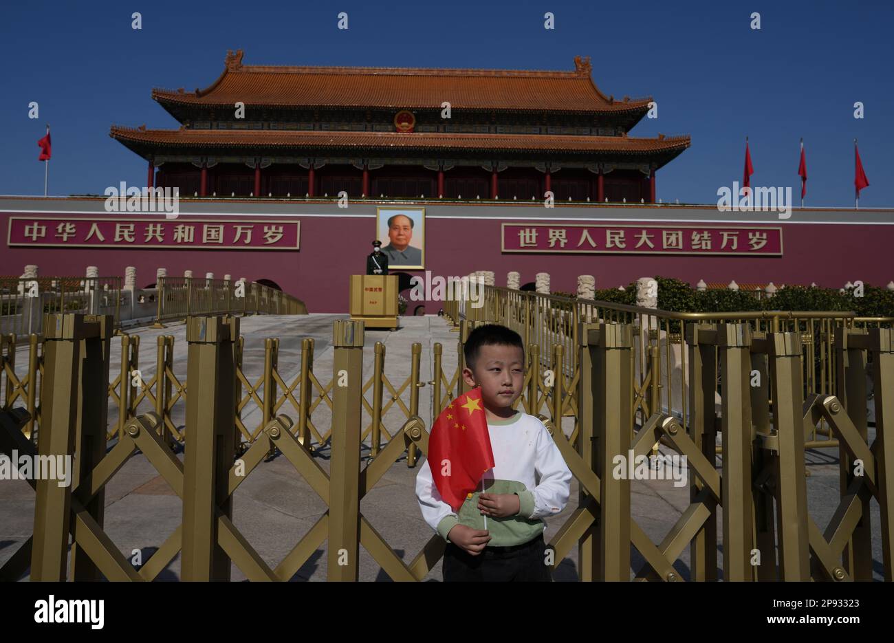 A boy holds with China National flag poses under a portrait of late ...