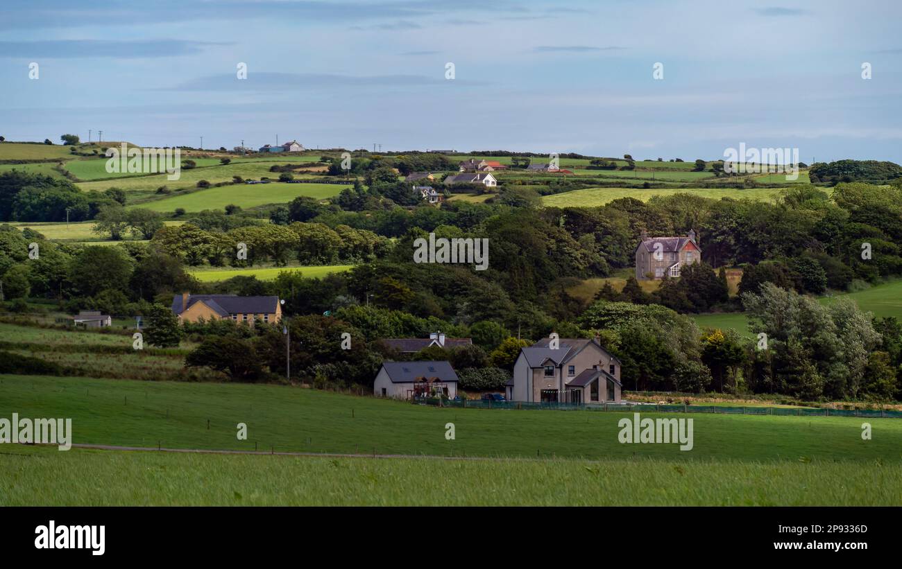 A European village among green fields, trees. Farmhouses in Ireland ...
