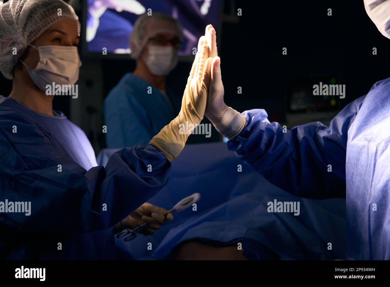 Doctors in operating room give high five after successful operation ...