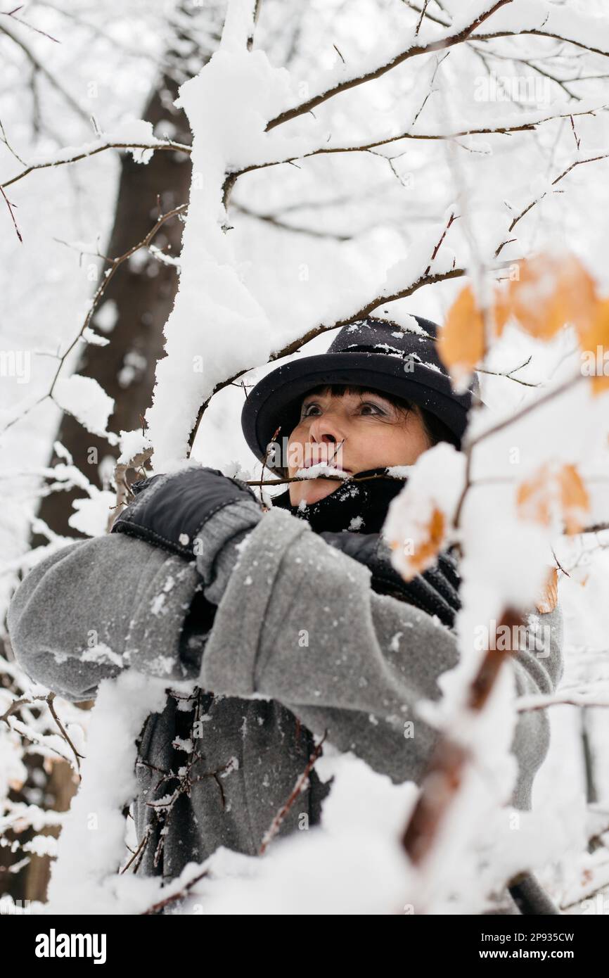 Woman in winter clothes holding on to a snowy tree Stock Photo - Alamy