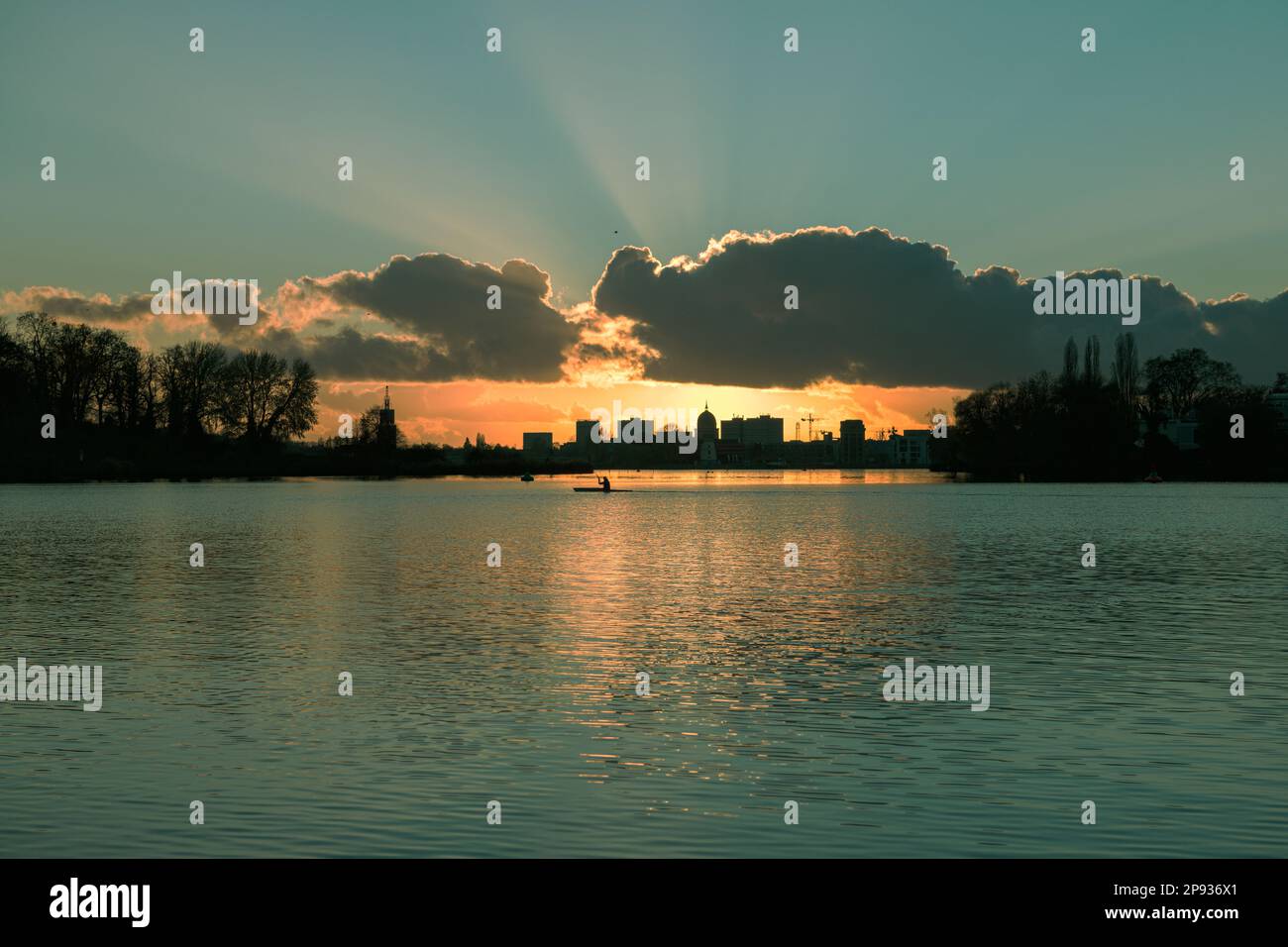 View over the deep lake in Potsdam to the sunset with canoeist and city ...