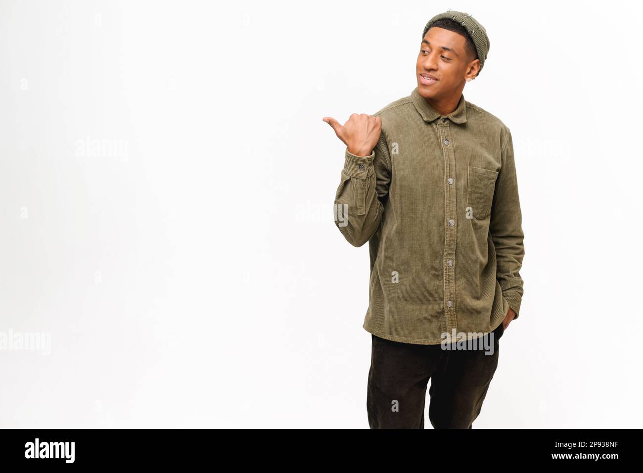 Attractive stylish young hispanic man wearing pointing aside with thumb ...