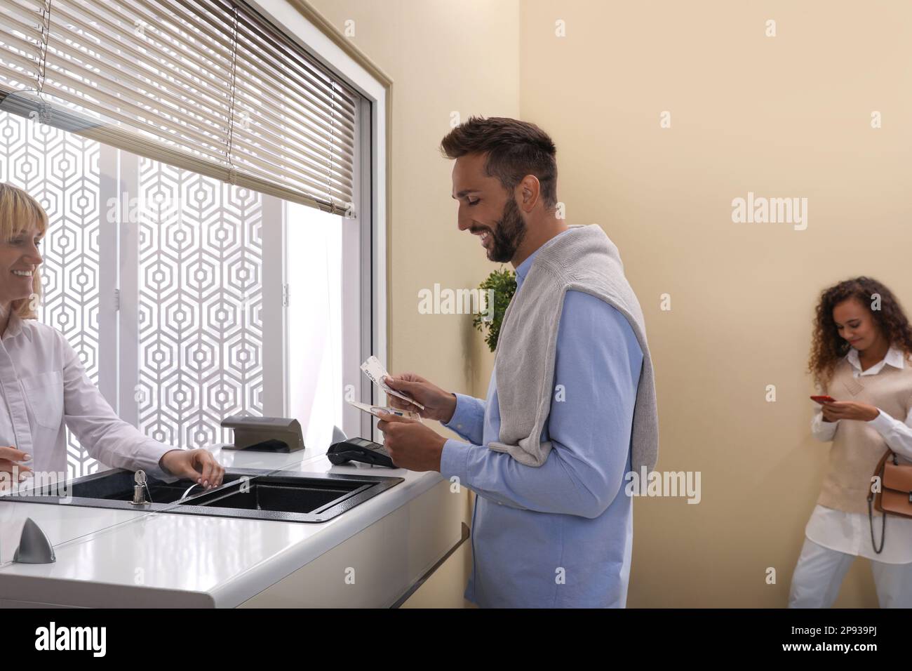 Man with money at cash department window in bank. Currency exchange ...
