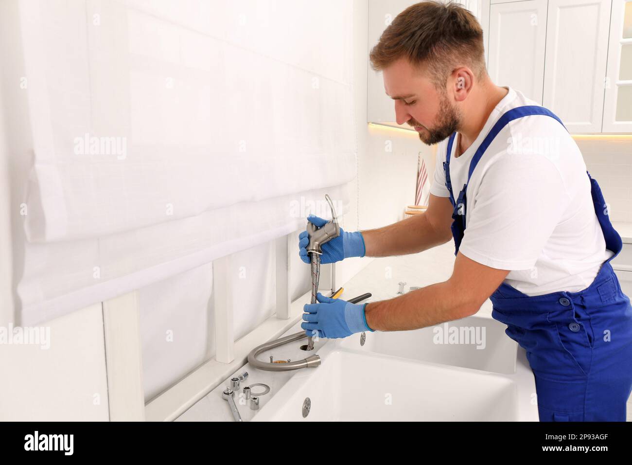 Professional plumber repairing water tap in kitchen Stock Photo - Alamy