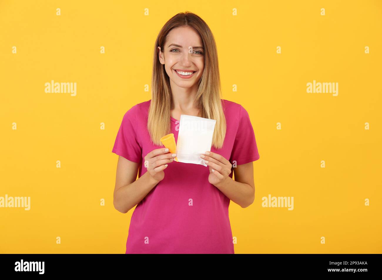 Happy young woman with menstrual cup and disposable pad on yellow ...