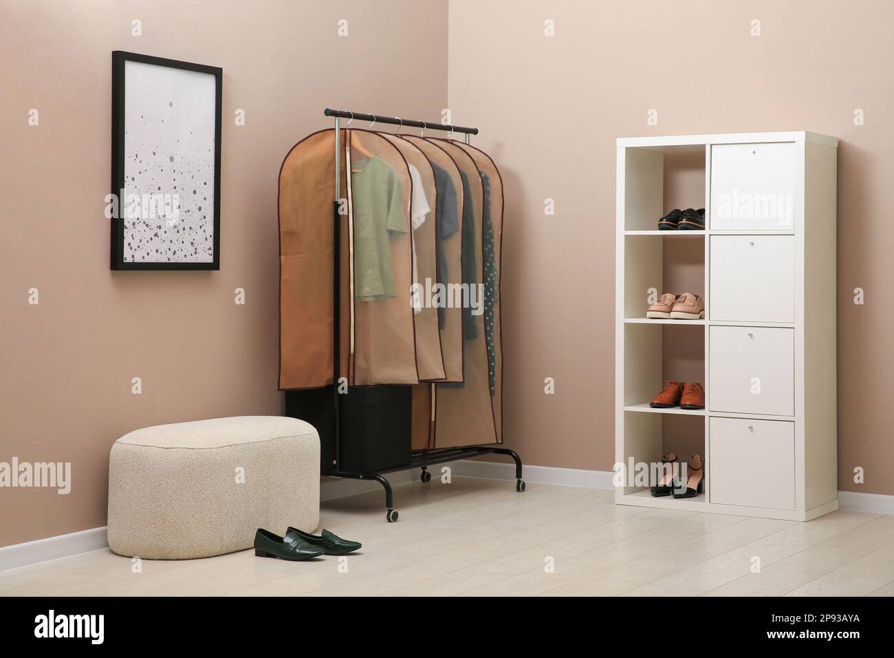 Garment bags with clothes hanging on rack in room Stock Photo - Alamy