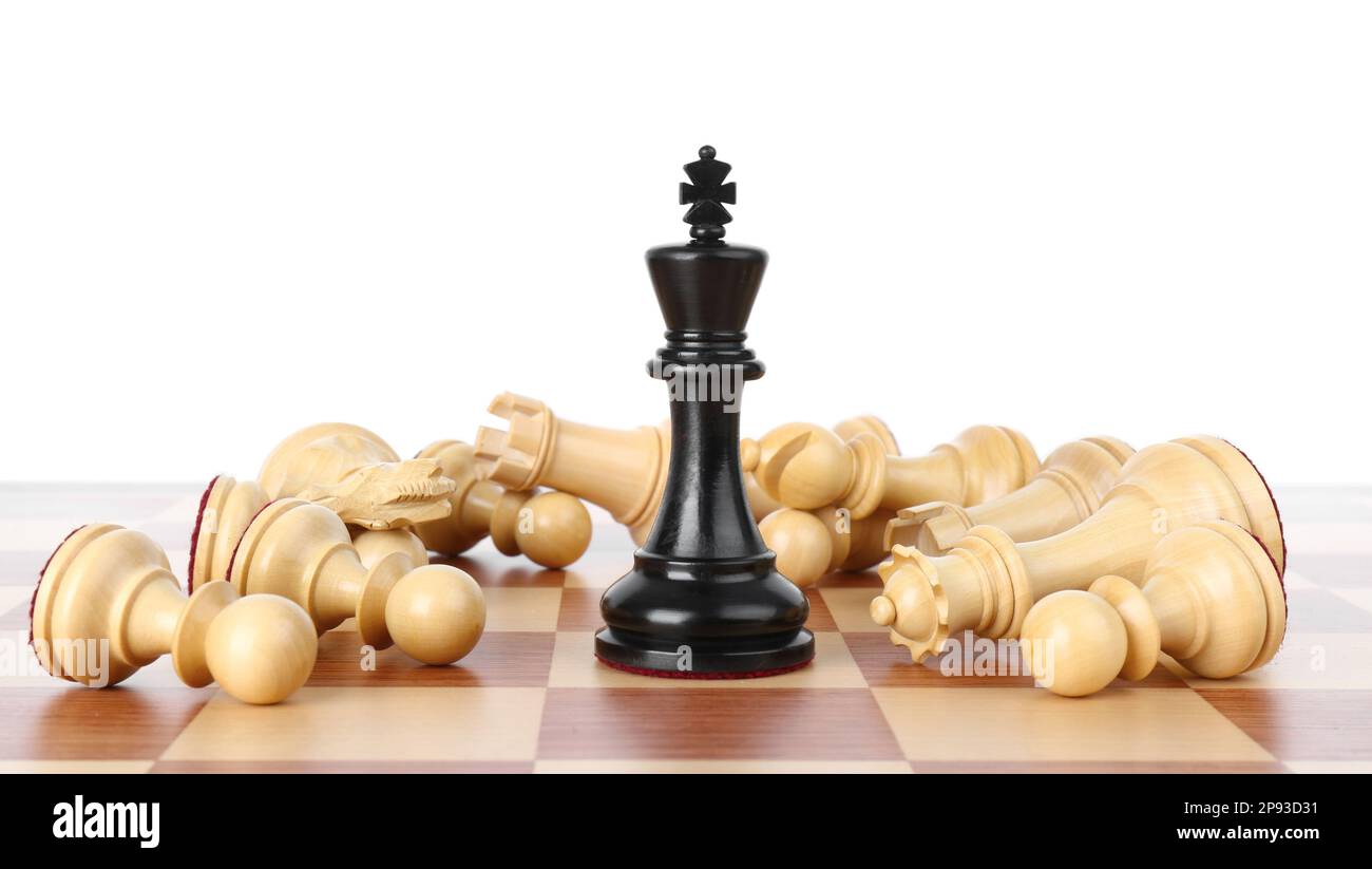 King among fallen chess pieces on wooden board against white background ...