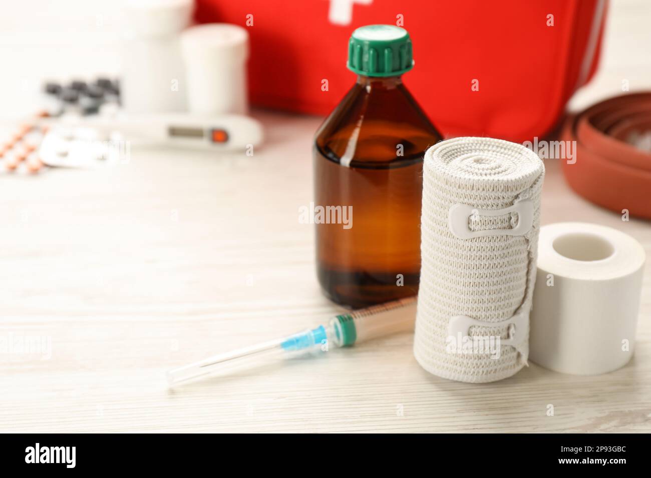 Bandage, sticking plaster roll, syringe and medicament on white wooden ...