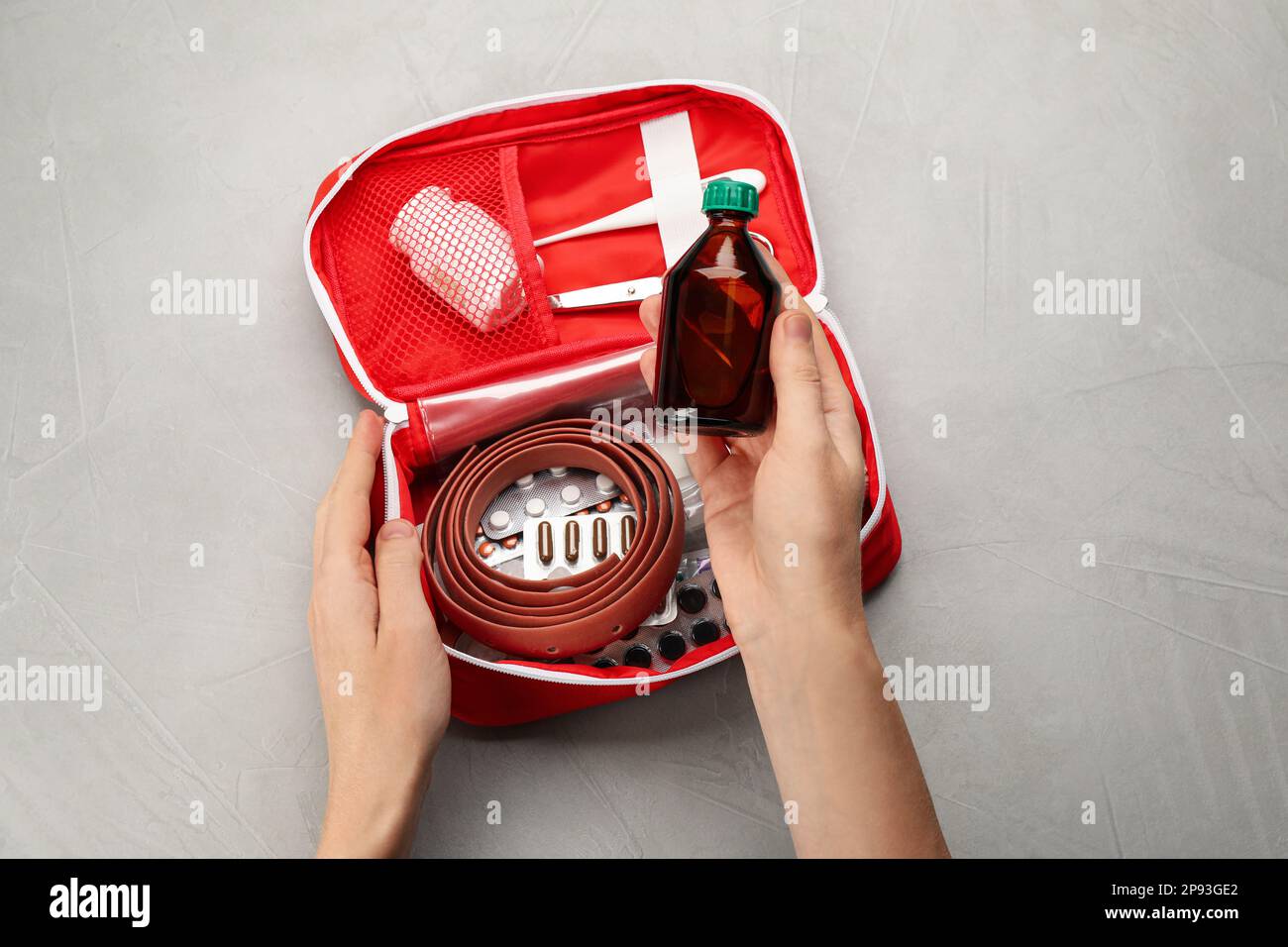 Woman taking medical alcohol from first aid kit at grey table, top view ...