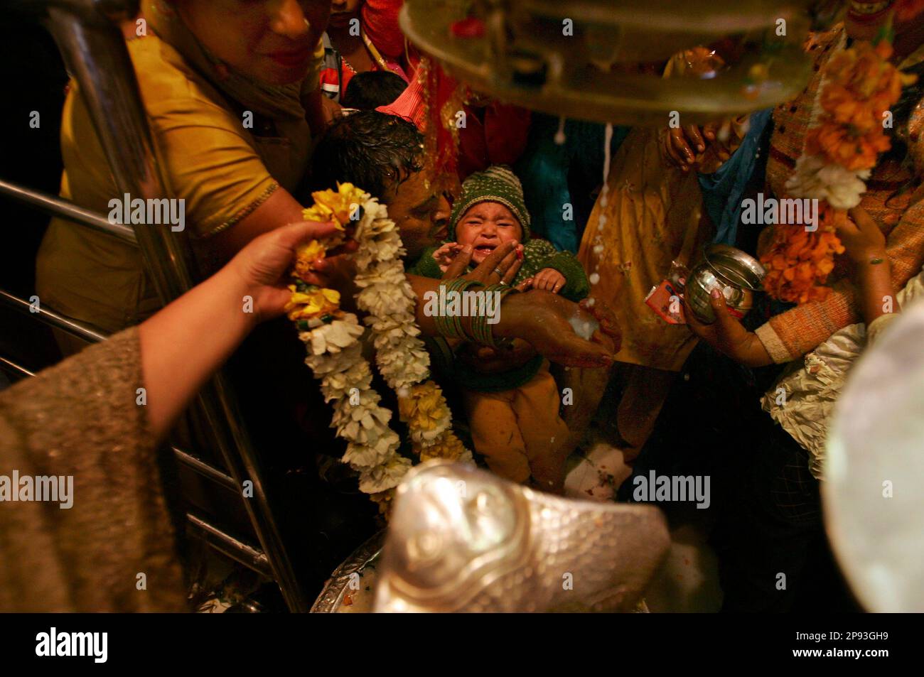 A child cries as devotees pour milk and other offerings at a Shivling ...