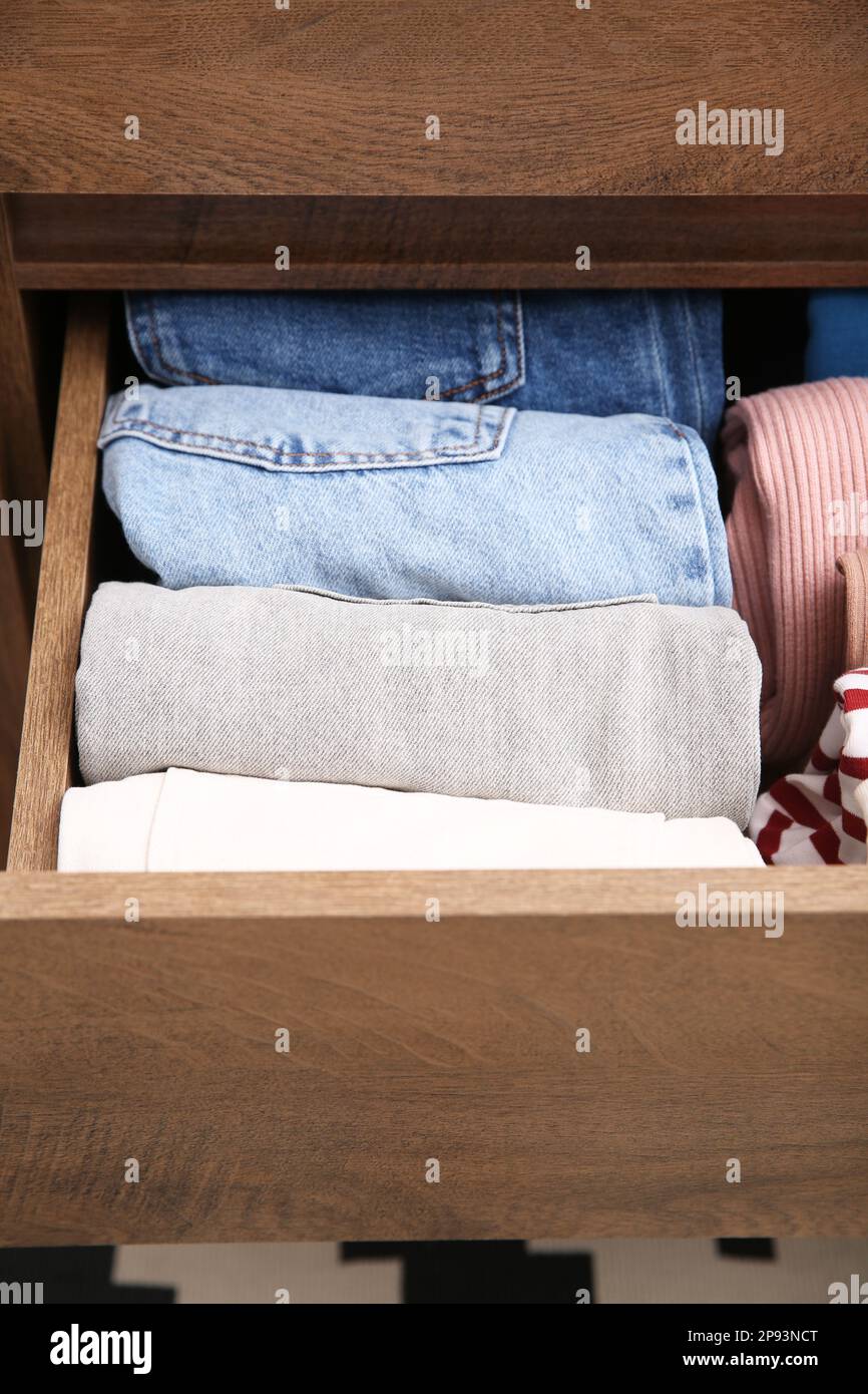 Open drawer with folded clothes indoors, closeup. Vertical storage ...
