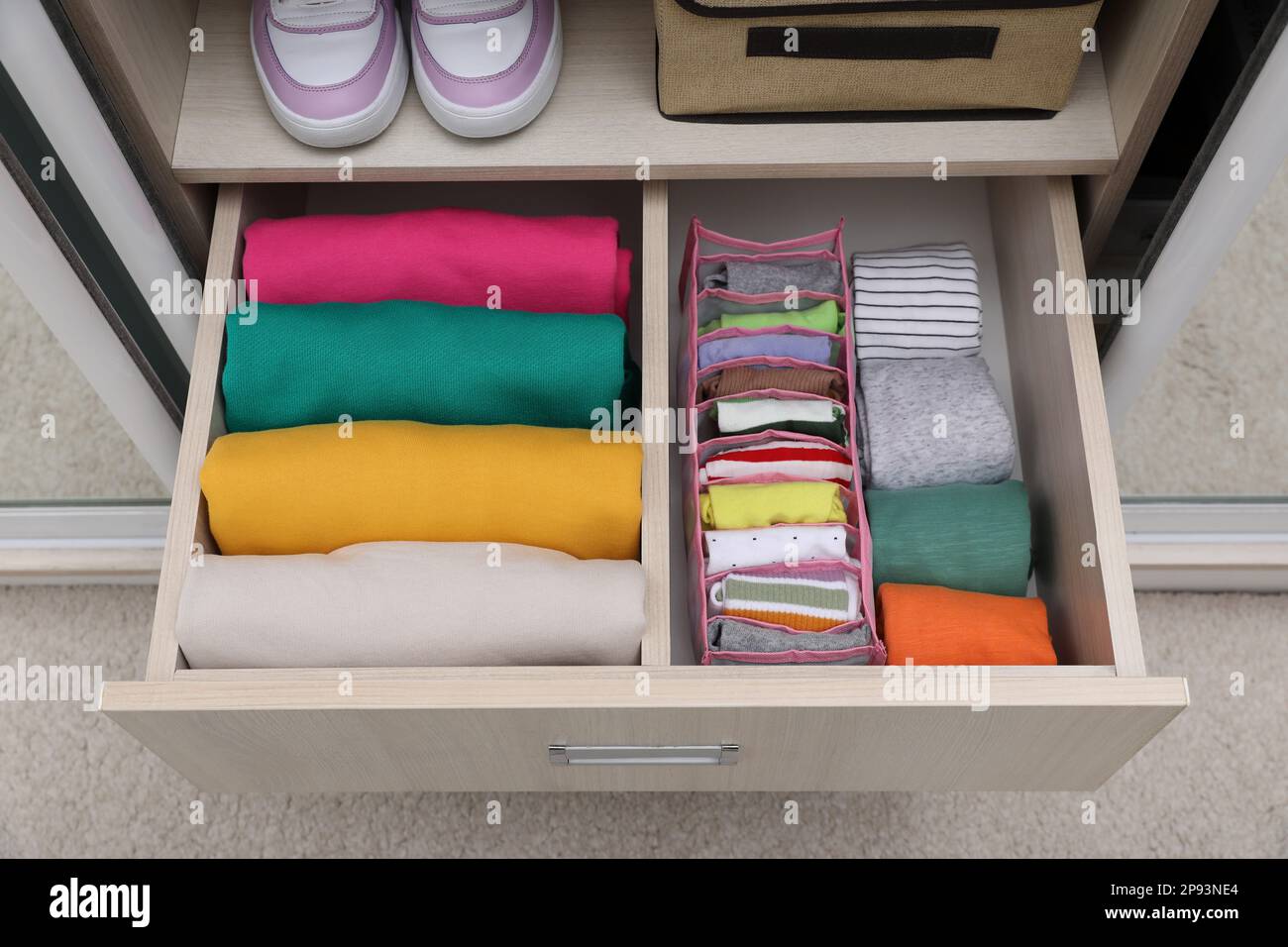 Wardrobe drawer with folded clothes and shoes, above view. Vertical ...