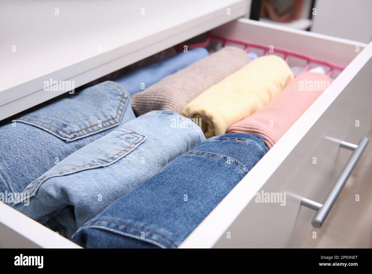 Open drawer with folded clothes indoors, closeup. Vertical storage ...