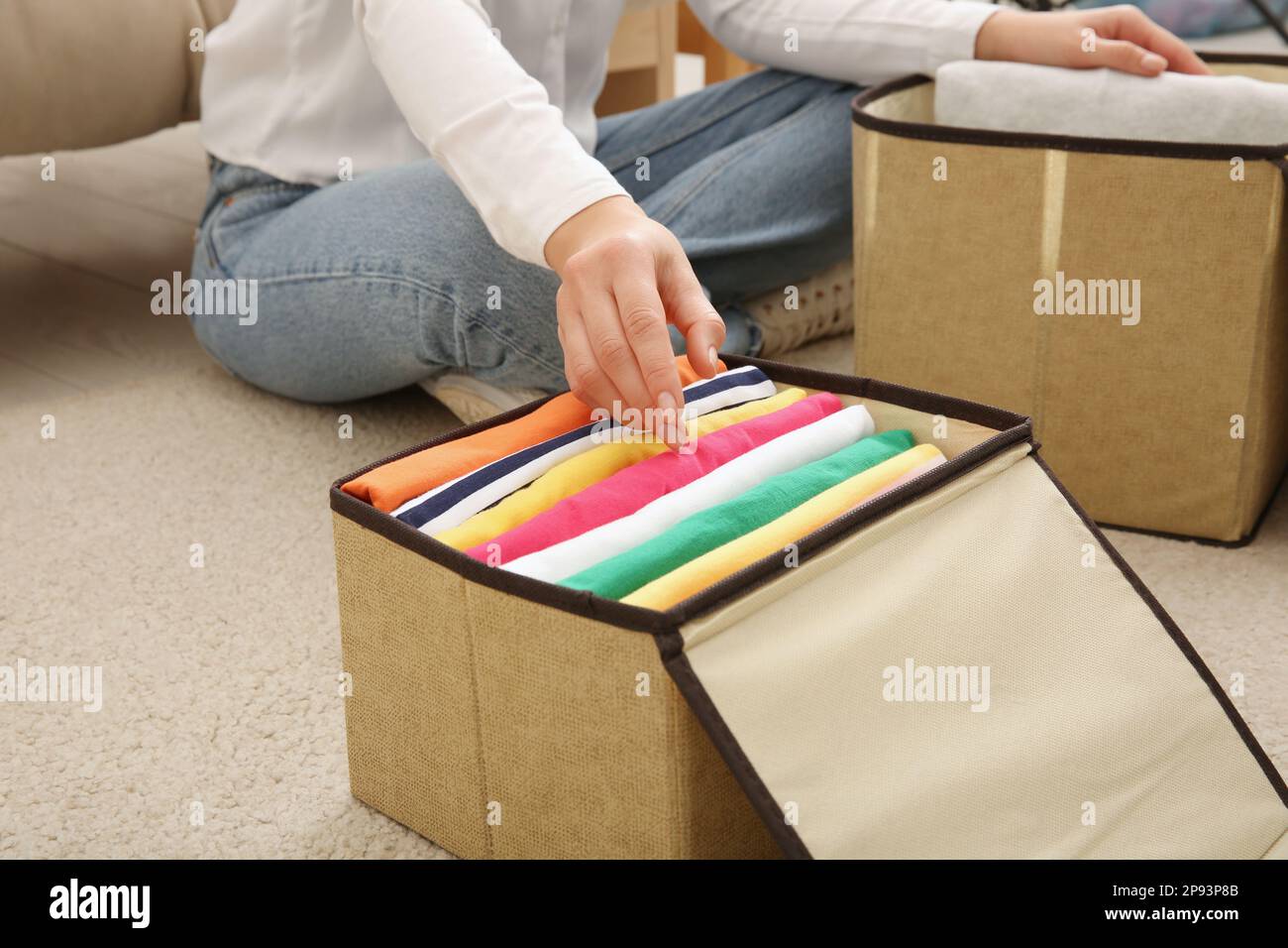 Woman folding clothes on floor at home, closeup. Japanese storage ...