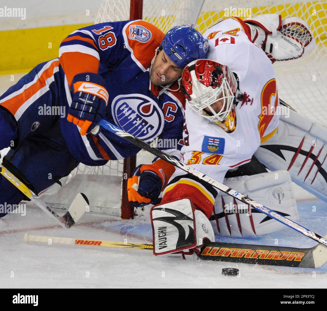 Edmonton Oilers' Ethan Moreau, left, falls on Calgary Flames' goalie ...